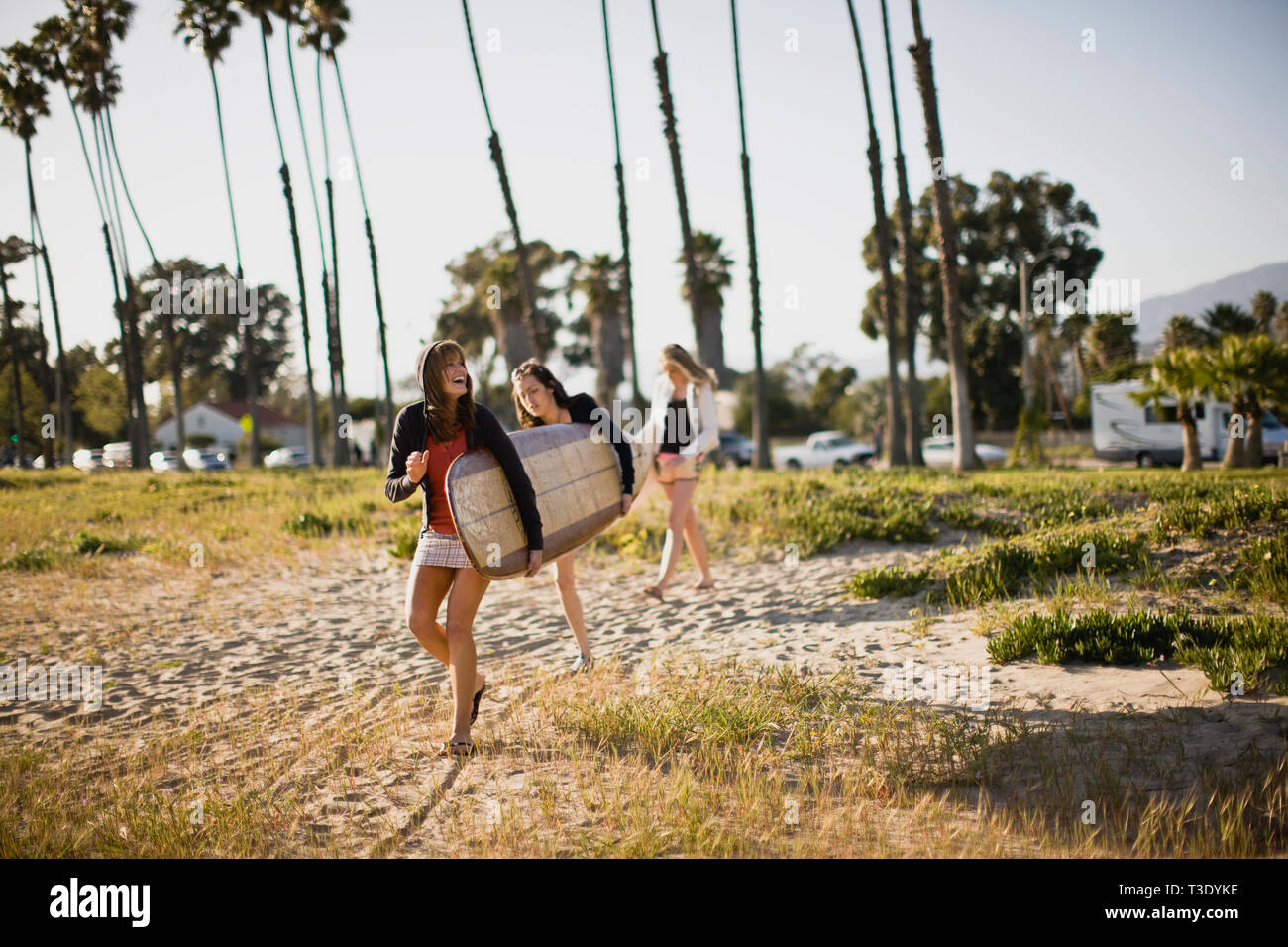 Young women carrying a surfboard on the beach Stock Photo - Alamy