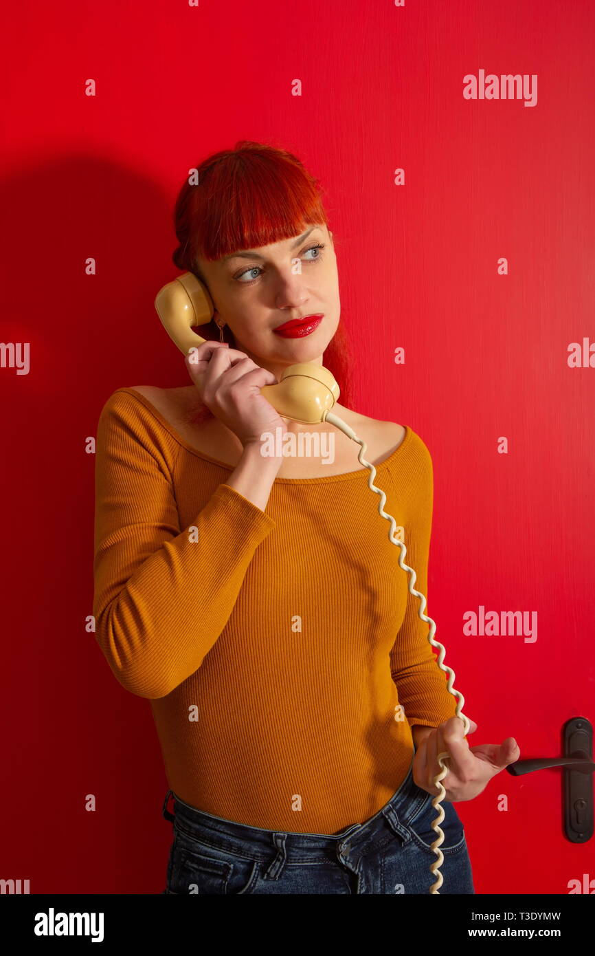 Pretty woman talking on an old dial telephone with a twisted wire on ...