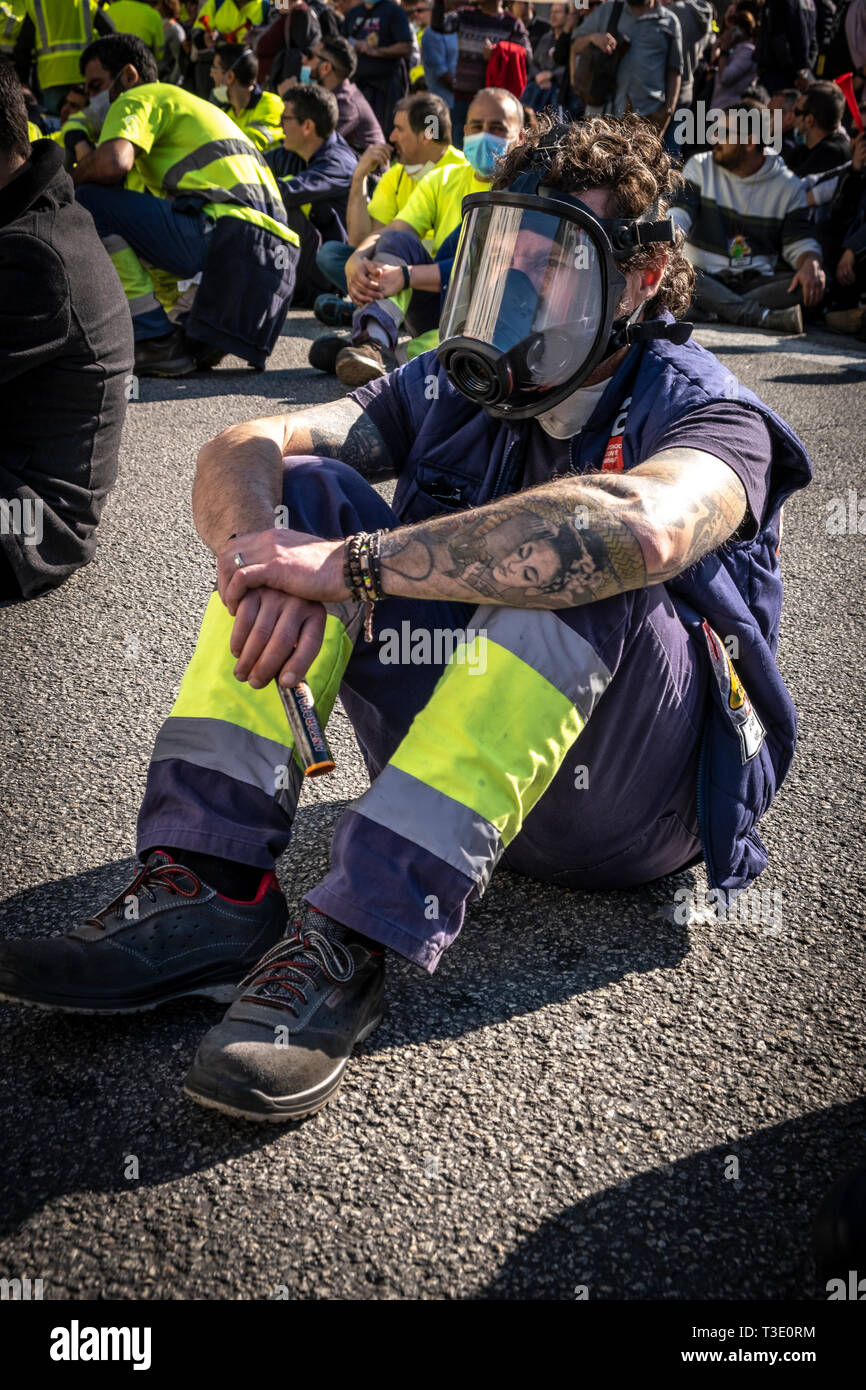 A worker is seen seated wearing an anti-gas mask during the protest ...