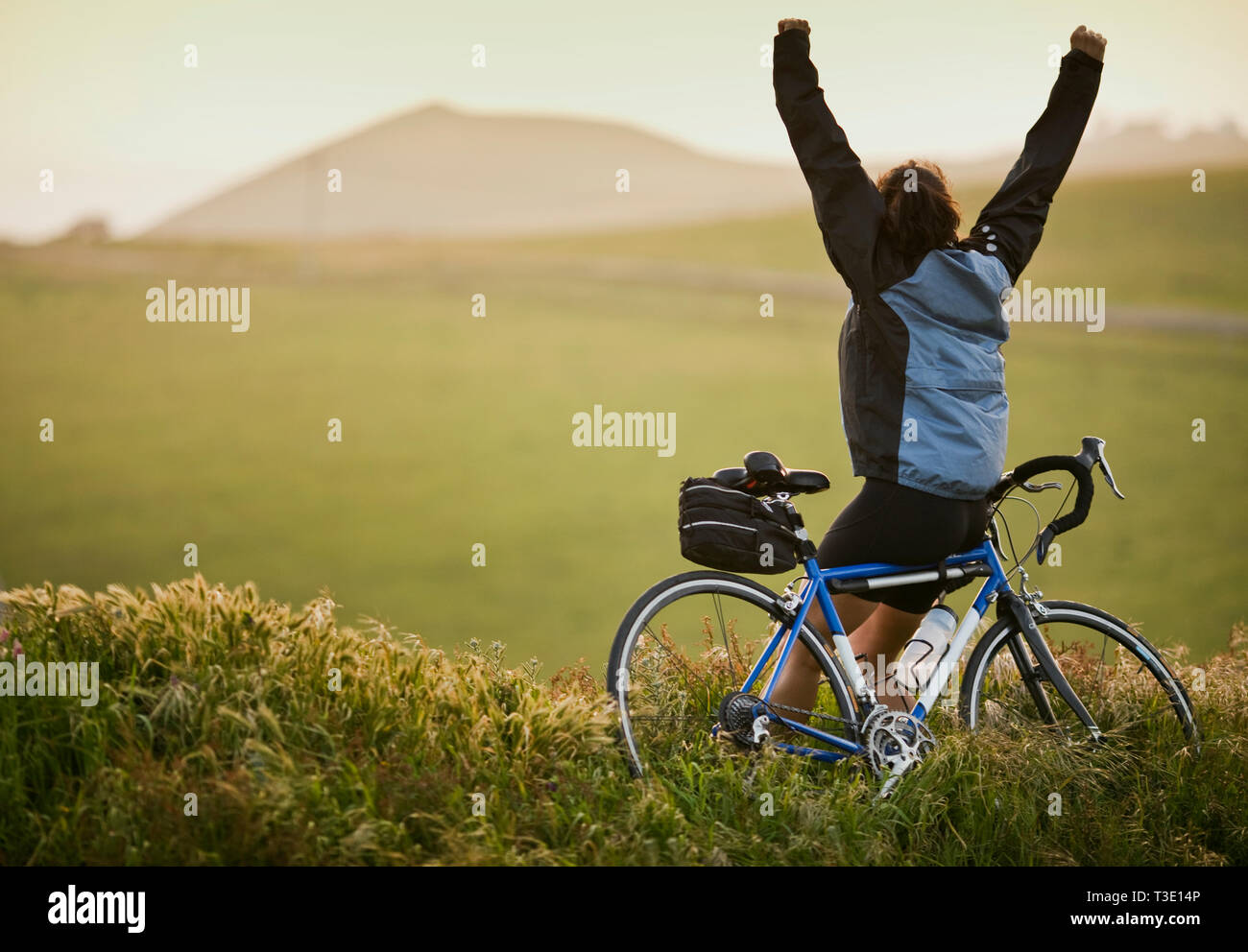 Female cyclist resting and raising her arms victoriously Stock Photo ...