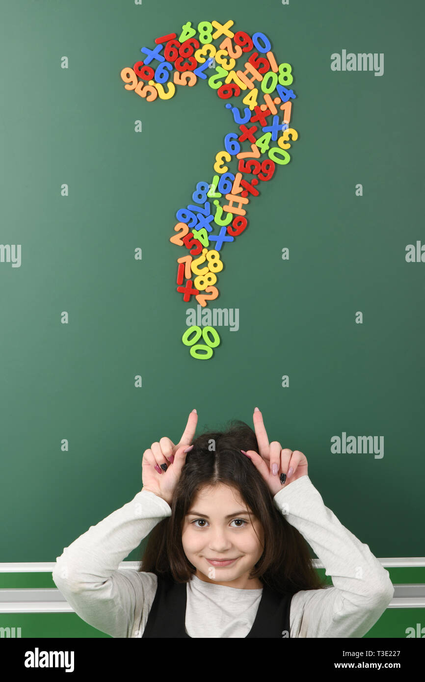 Smiling little schoolgirl on green school board. A magnetic question ...