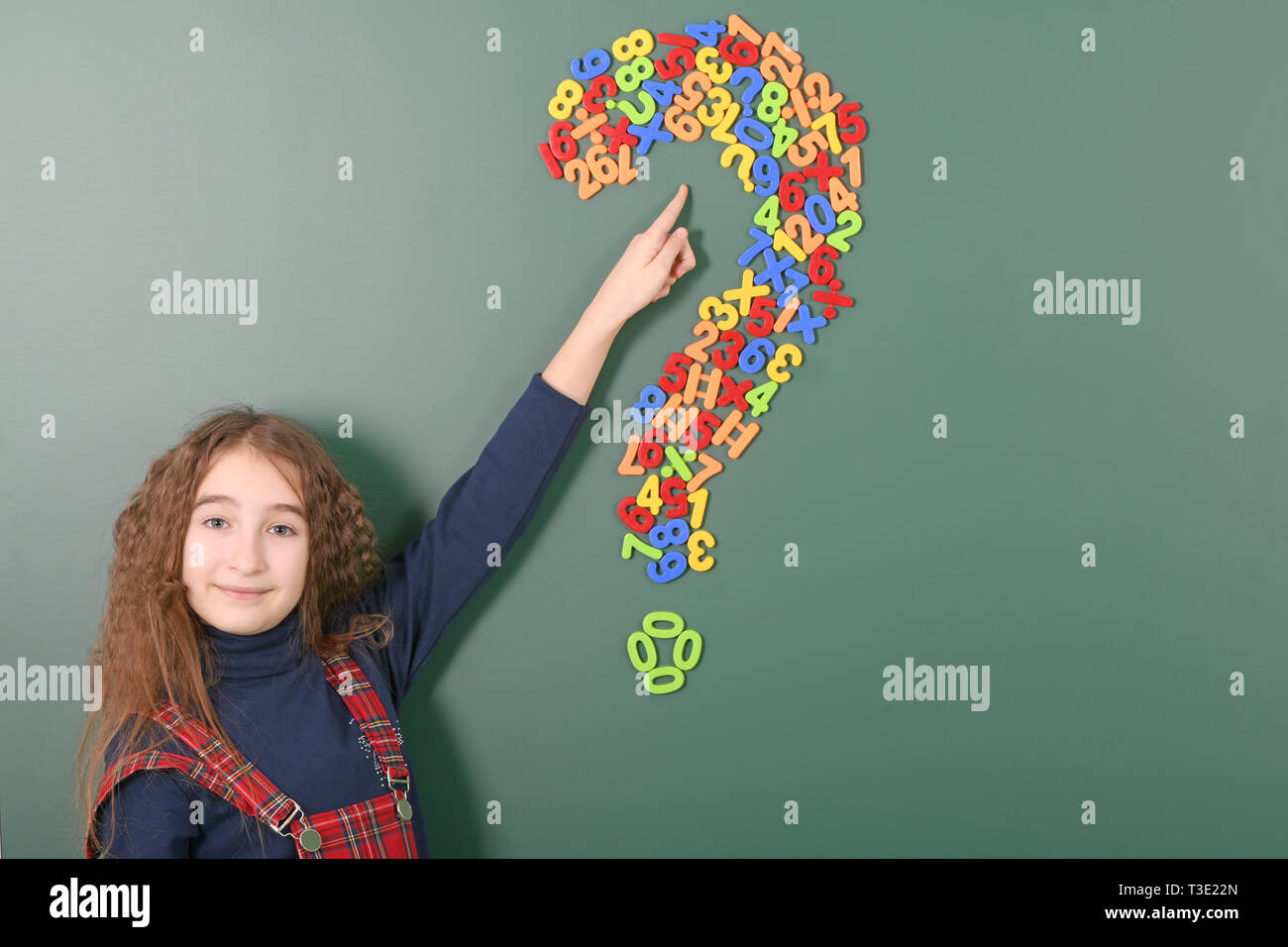 Smiling little schoolgirl on green school board. A magnetic question ...