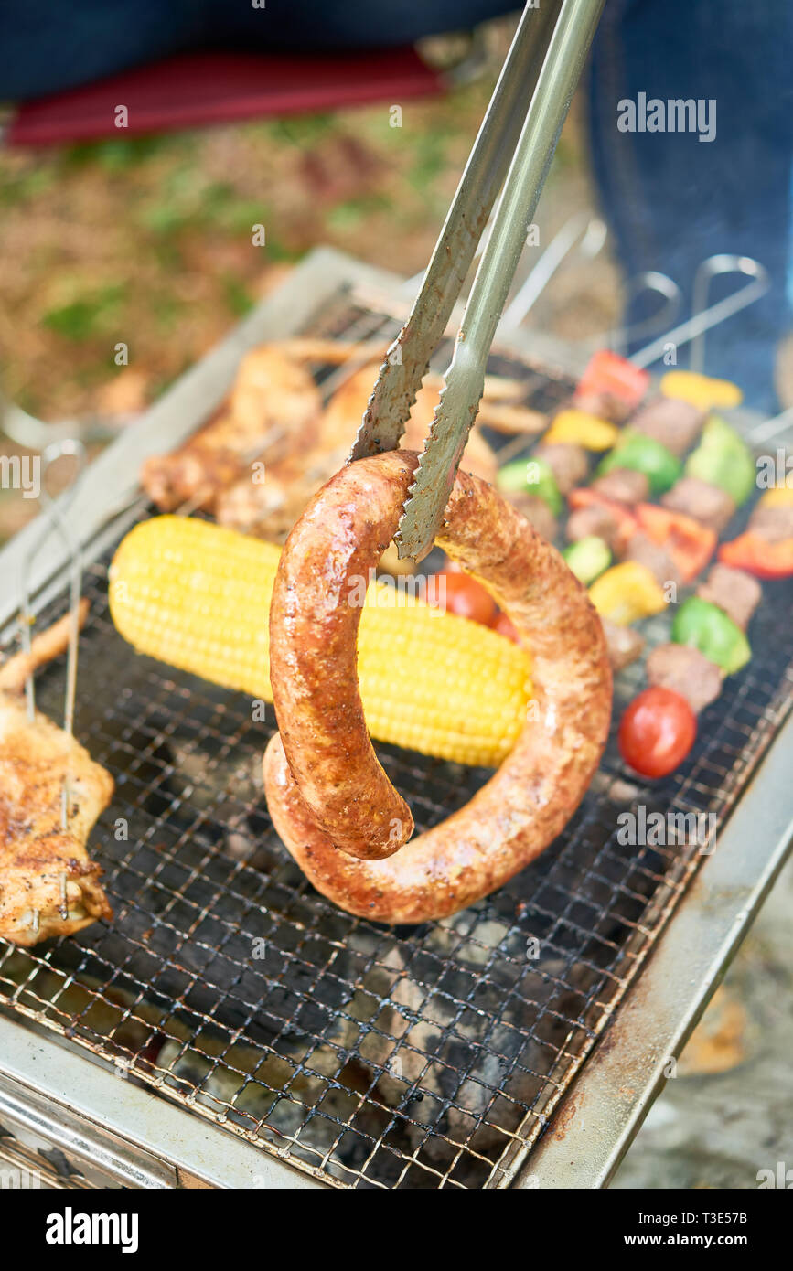 Turning sausage on grill Stock Photo - Alamy