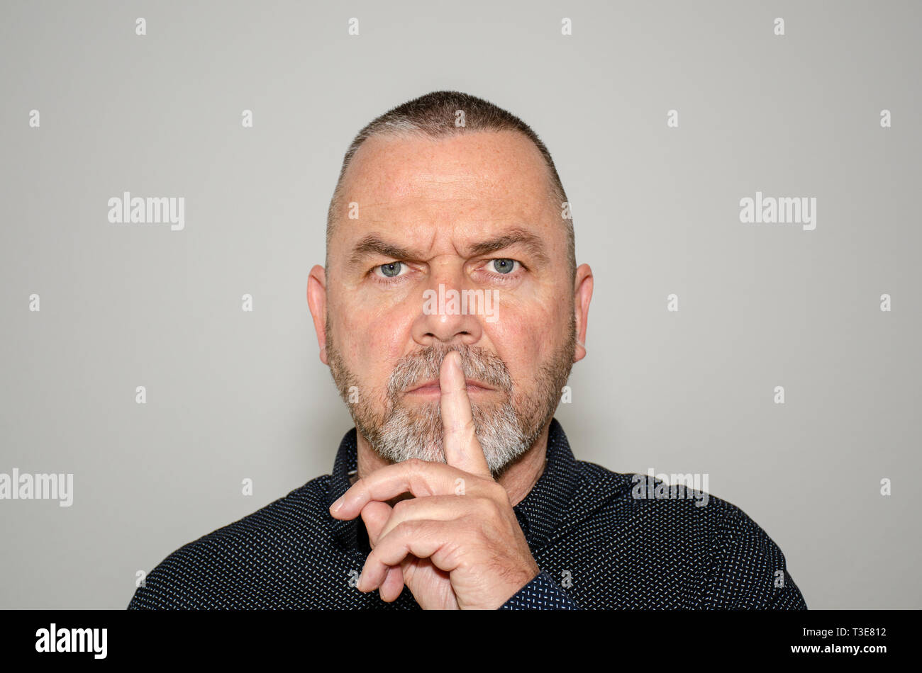Man making a hush gesture with finger to lips as he asks for silence or ...