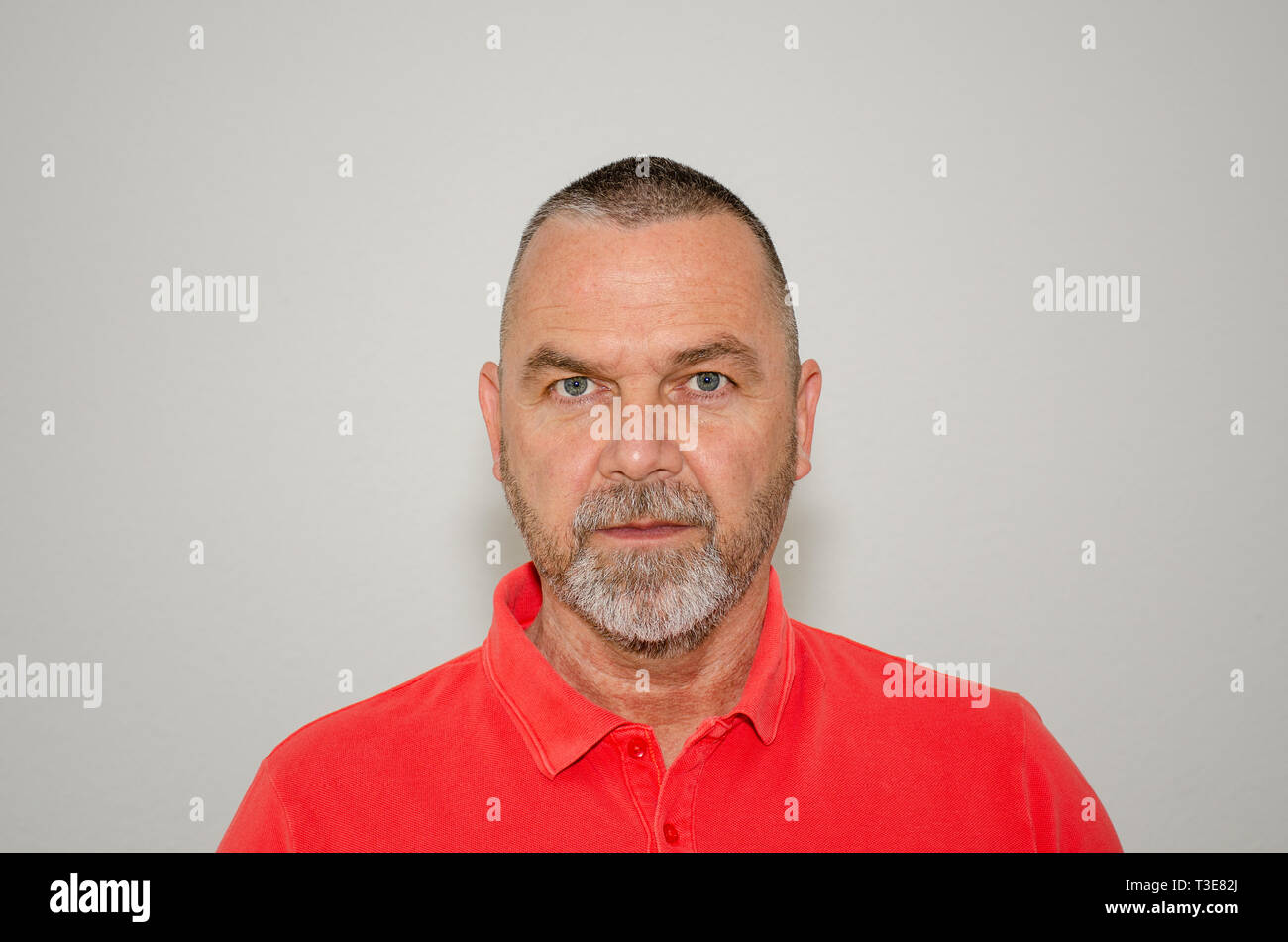 Intense middle-aged man with an enigmatic deadpan expression staring at ...