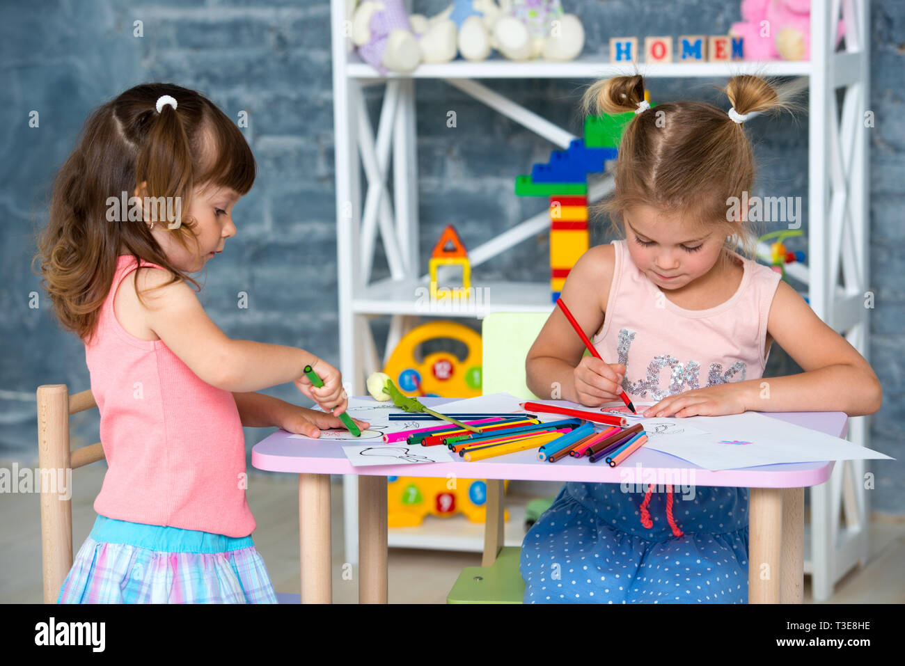 Two little beautiful girls draw with colorful pencils Stock Photo - Alamy