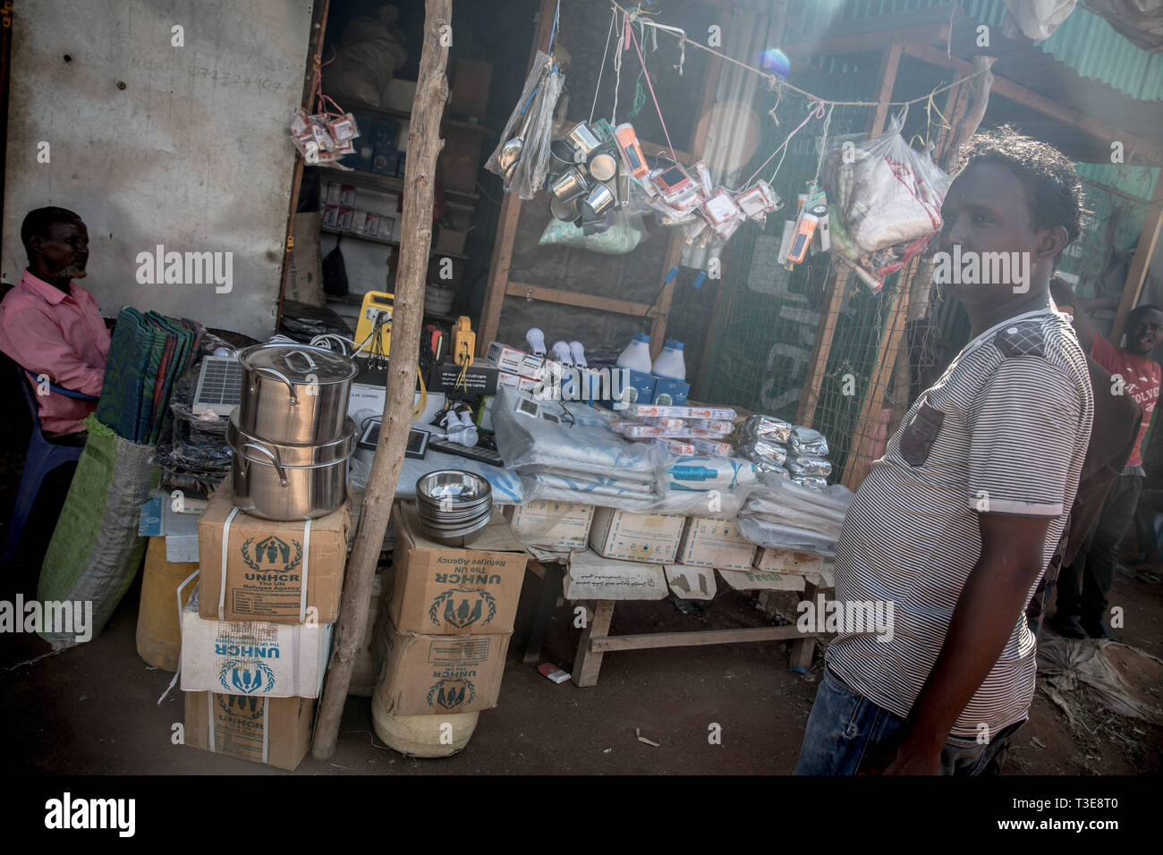 A refugee seen standing in front of a shop stand where UNHCR ...