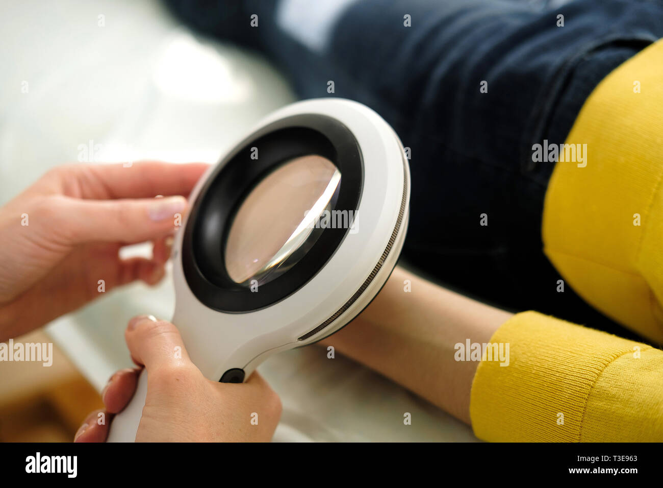 Dermatologist using a professional magnifying glass while doing skin ...