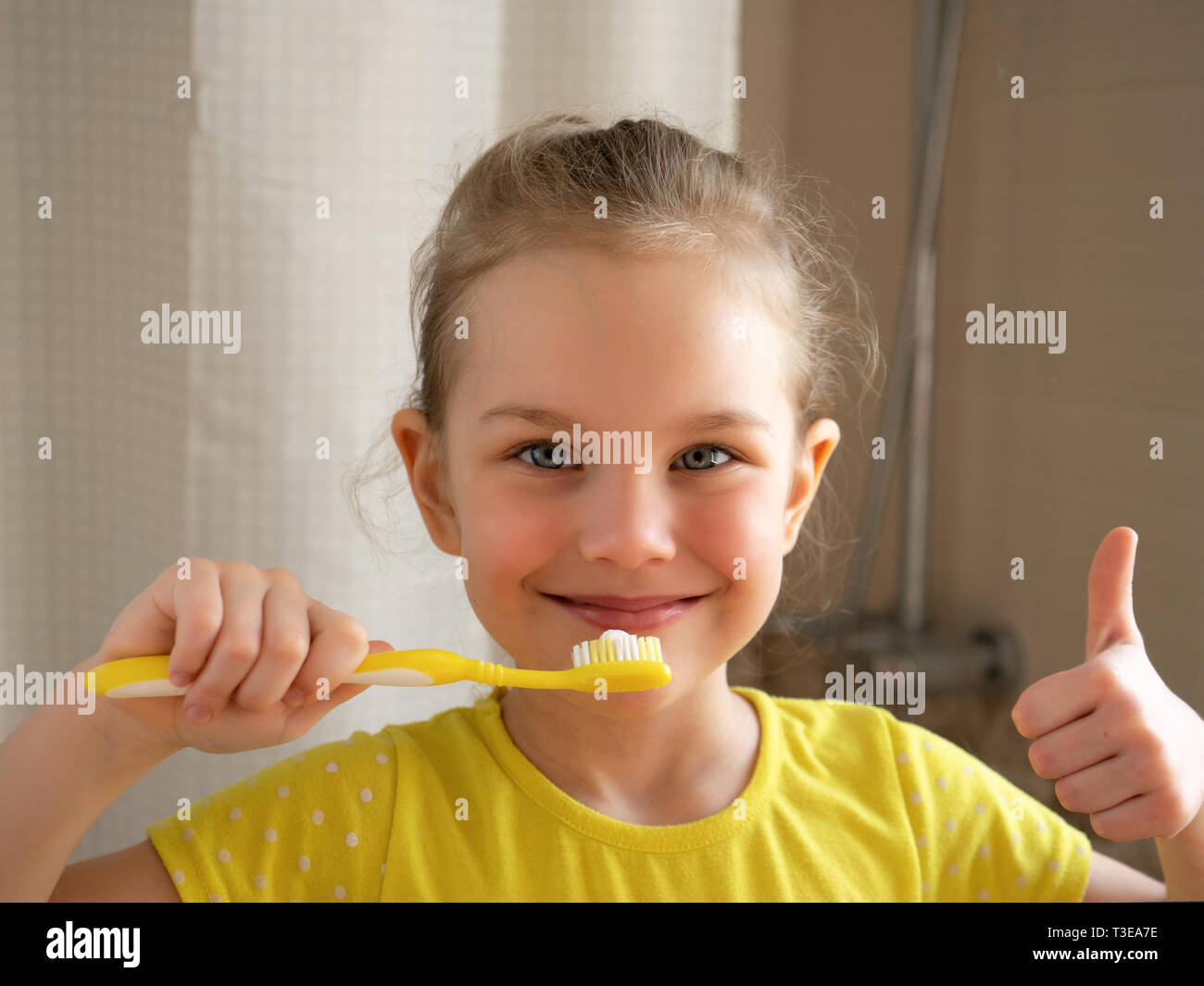 Little cute blond girl brushes her teeth with a toothbrush in the ...