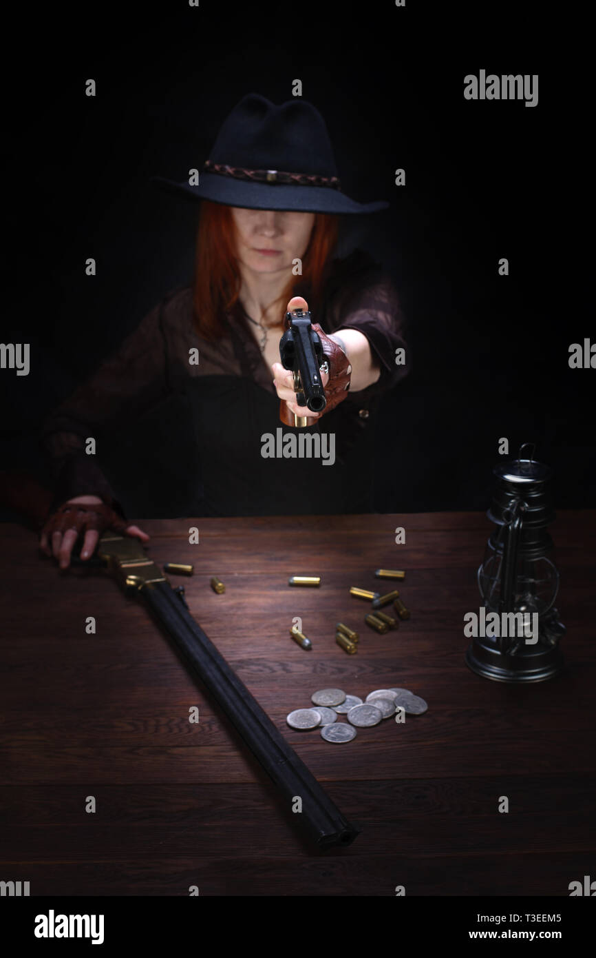 wild west girl with revolver gun sitting at the table with ammunition ...