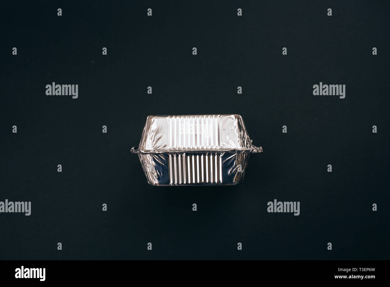 Stop plastic pollution. Aluminum foil silver container for food on dark ...