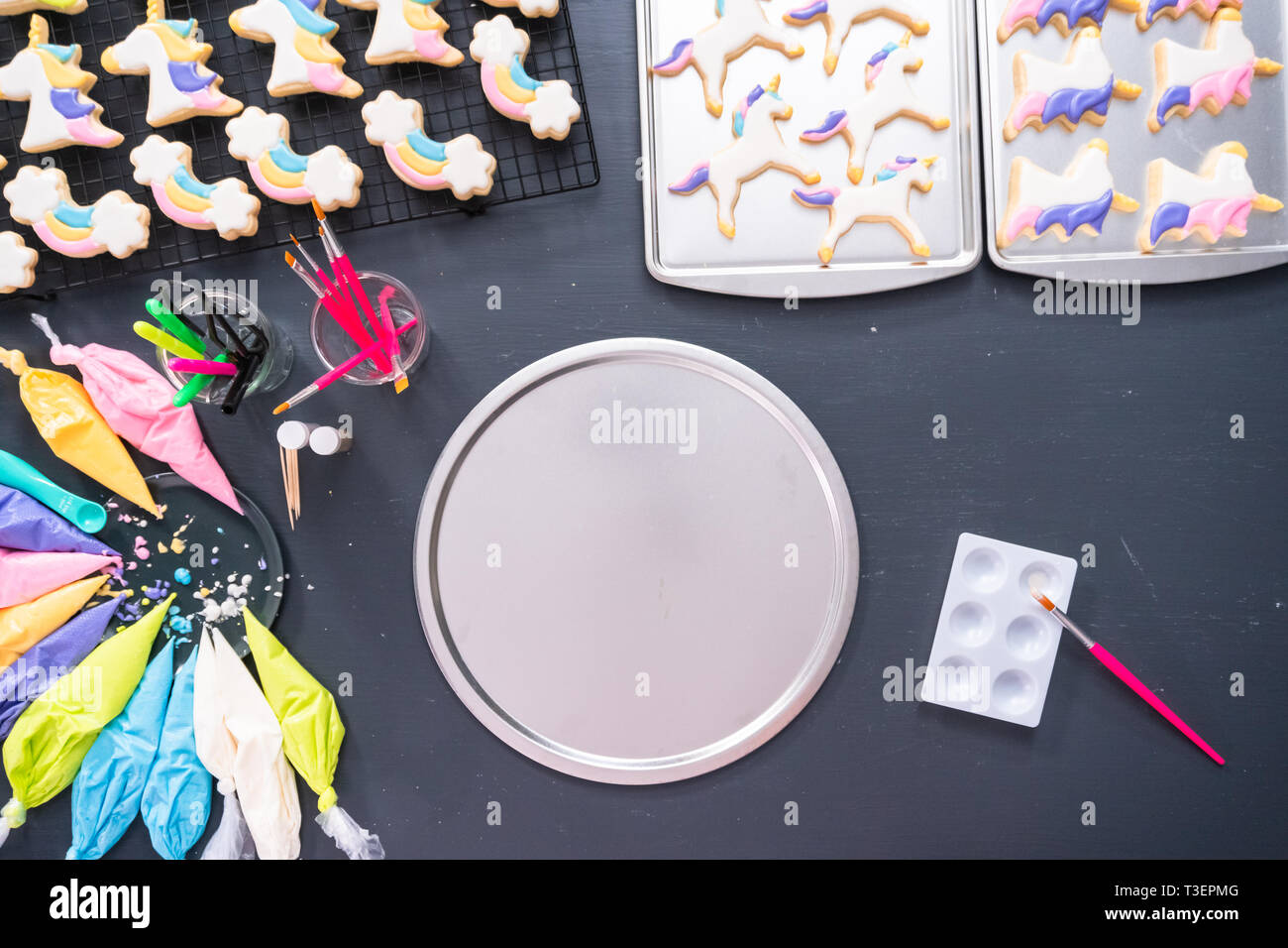 Flat lay. Decorating unicorn shaped sugar cookies with royal icing ...