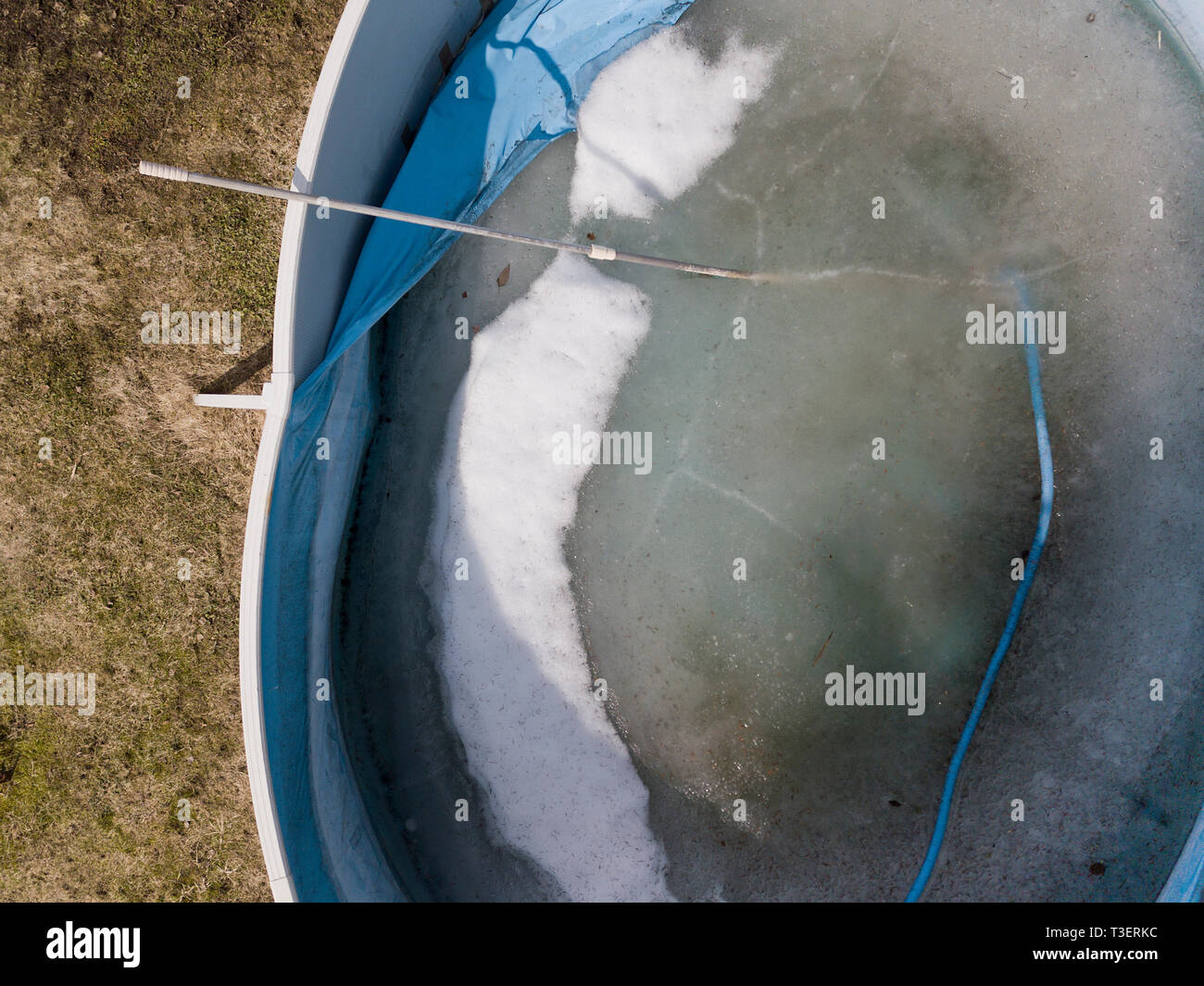 Overhead view of a swimming pool with damaged plastic full of melting ...