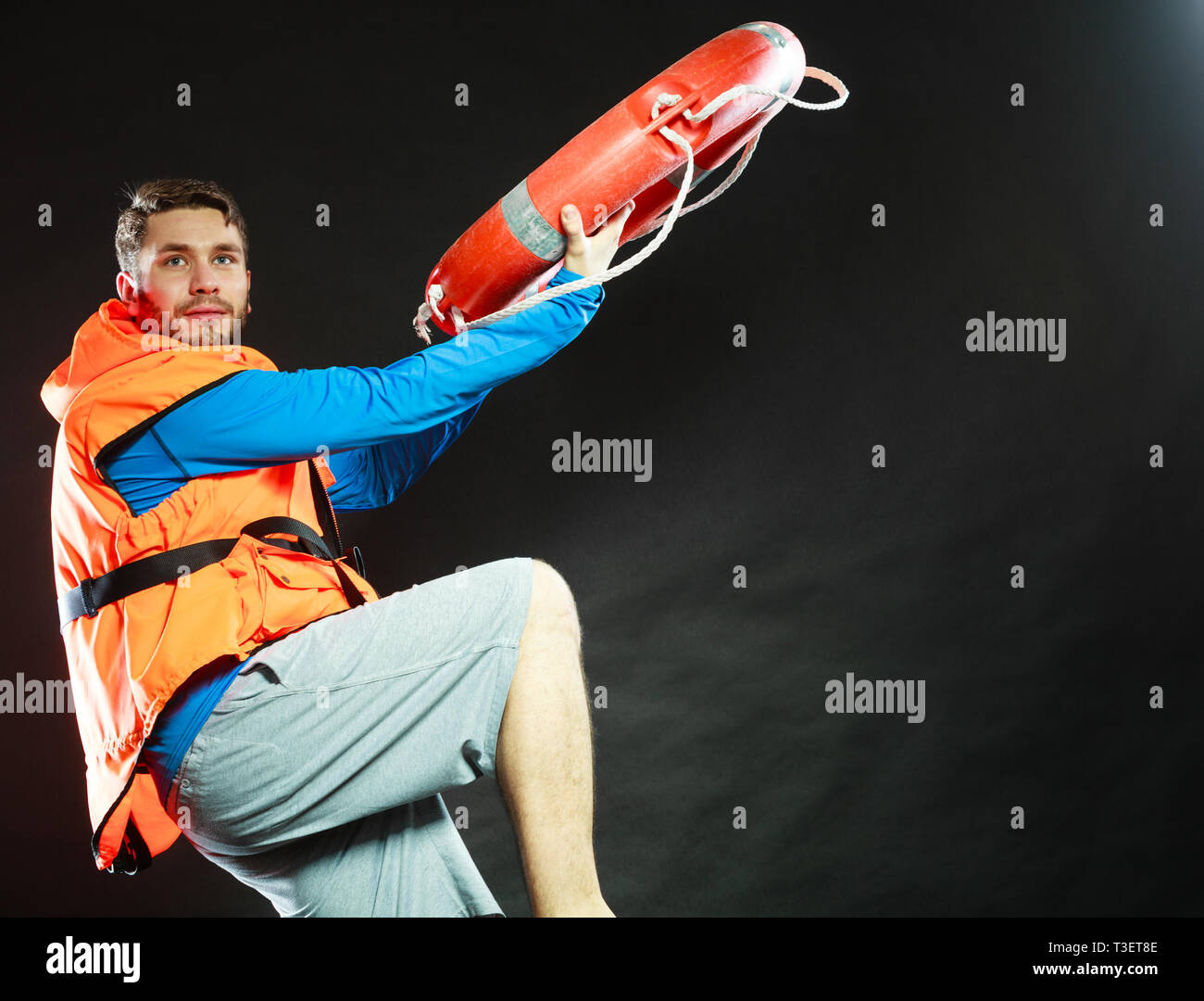 Lifeguard in life vest jacket throwing ring buoy lifebuoy. Man ...