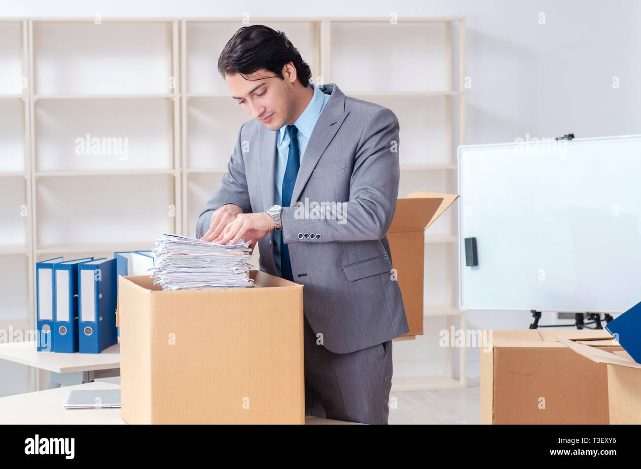Young man employee with boxes in the office Stock Photo - Alamy