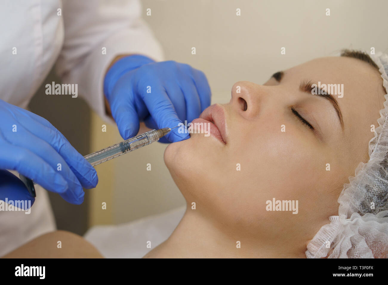 Aesthetic cosmetology. Lip augmentation in spa salon. Beautician makes ...