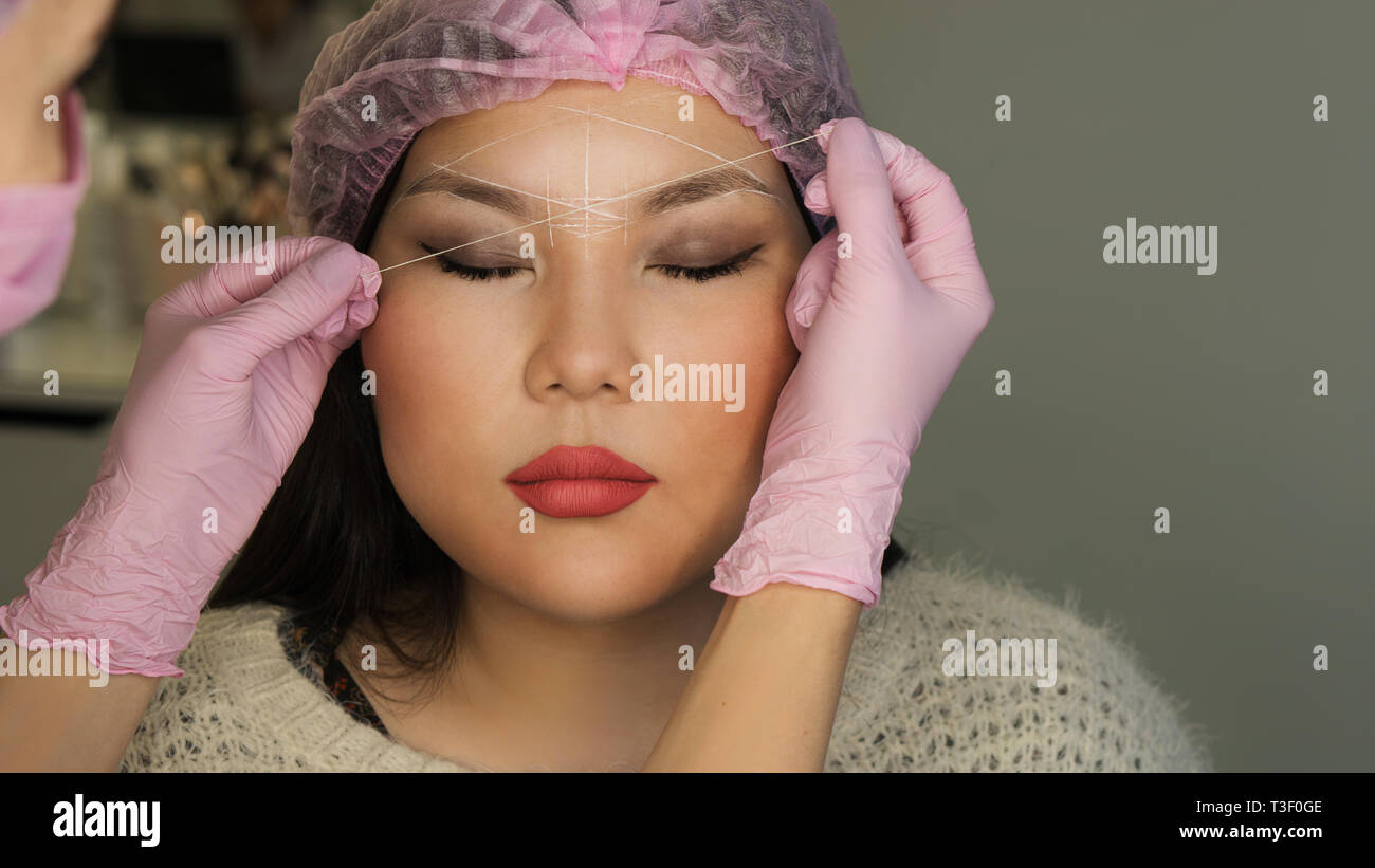 Microbleeding and eyebrow architecture. beautician builds lines of ...