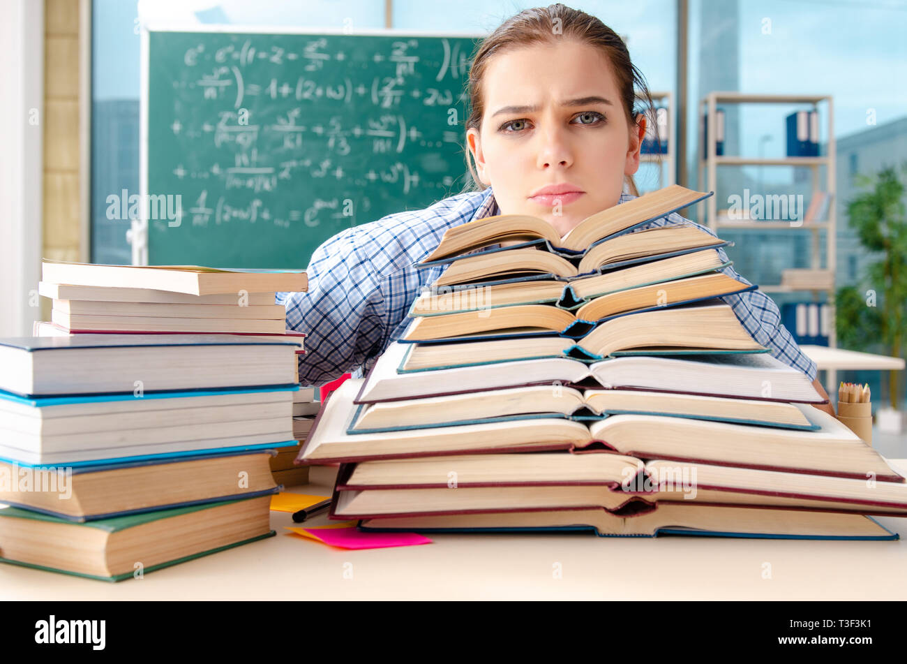 Female student with many books sitting in the classroom Stock Photo - Alamy
