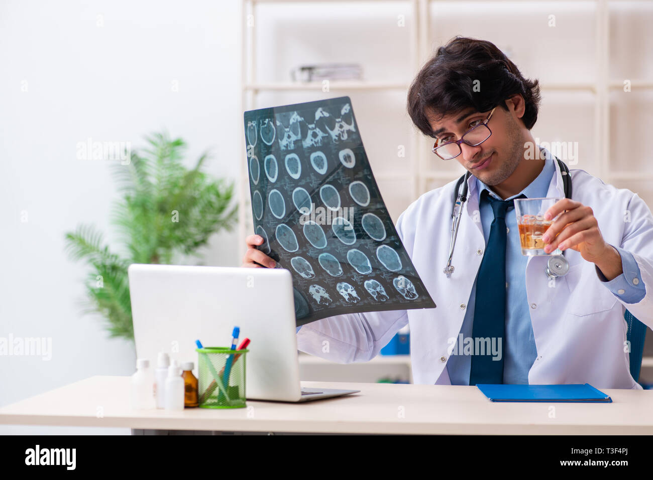 Young male doctor drinking in the office Stock Photo - Alamy