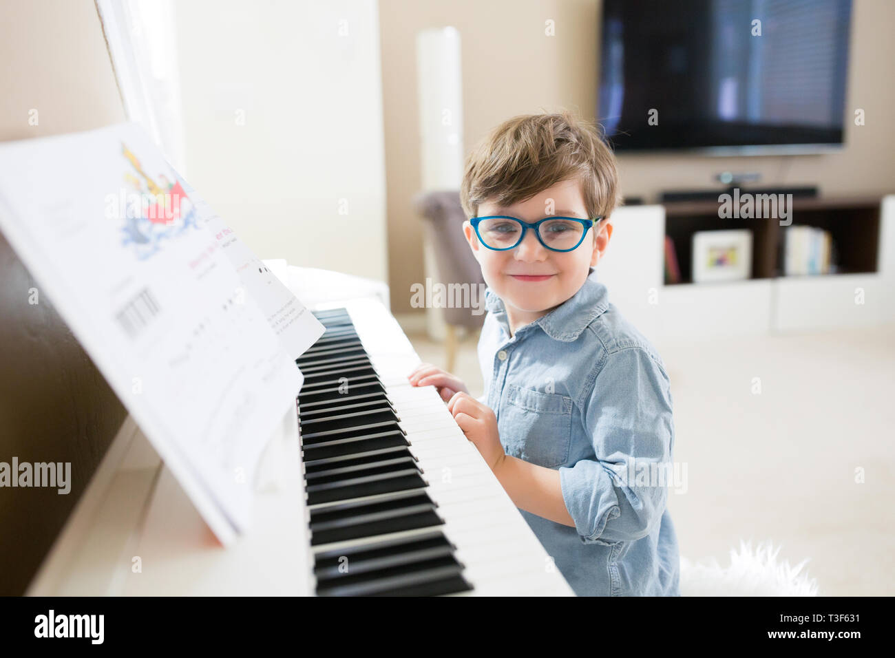 Little boy looking at the camera when playing piano Stock Photo - Alamy
