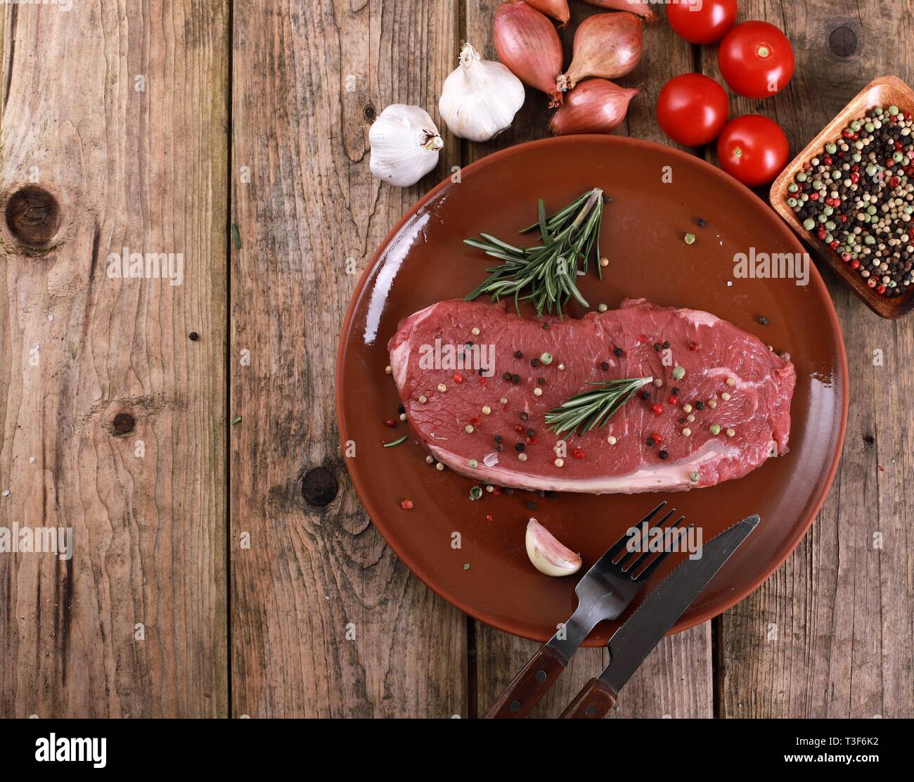 raw rumpsteak beef steak with rosemary, pepper, tomatos and spices on a ...