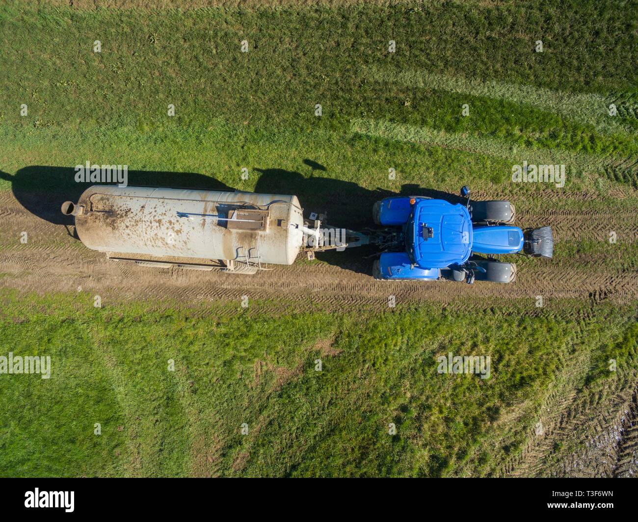 aerial view of a blue tractor with a fertilizer trailer on agricultural ...