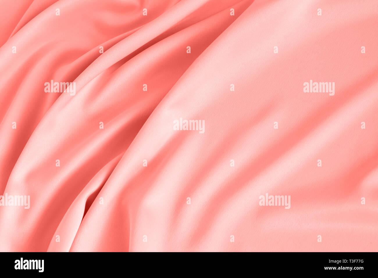 Close up of ripples on silk fabric in coral pink color. Satin textile ...