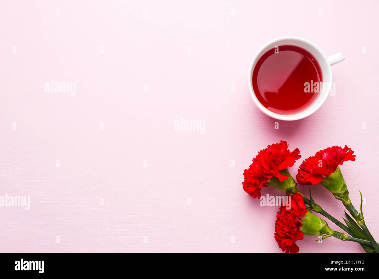 Red-pink objects. Cup of tea, carnation flowers Notepad for text on ...