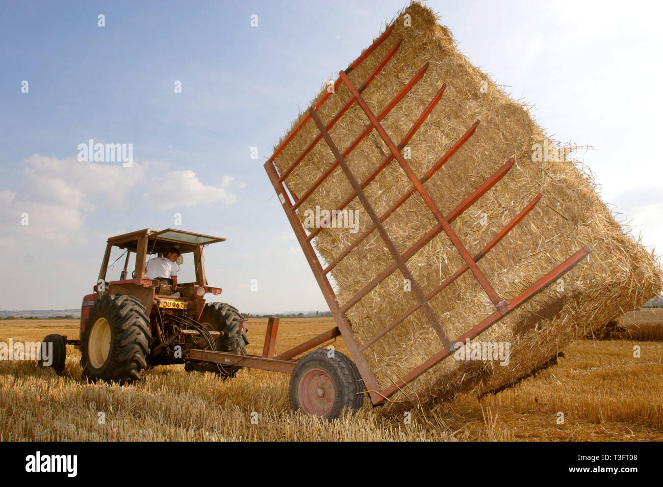 Bails of hay being driven off the land for storage in the farm yard ...