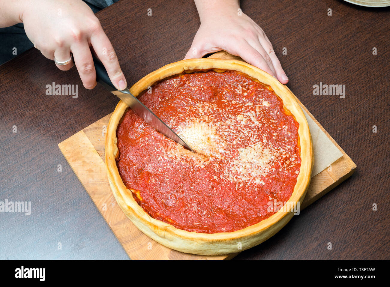 Top view of Chicago pizza. Woman hands cutting Chicago style deep dish ...