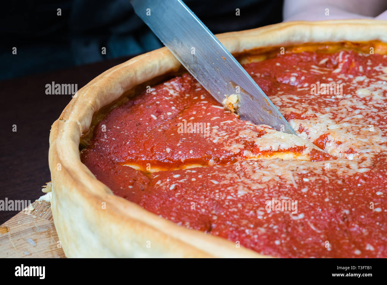Top view of Chicago pizza. Woman hands cutting Chicago style deep dish ...