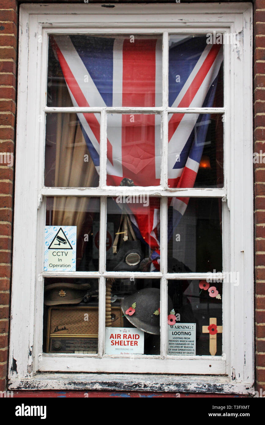 Pawn shop window with air shelter sign, hat, UK Union jack flag, among ...