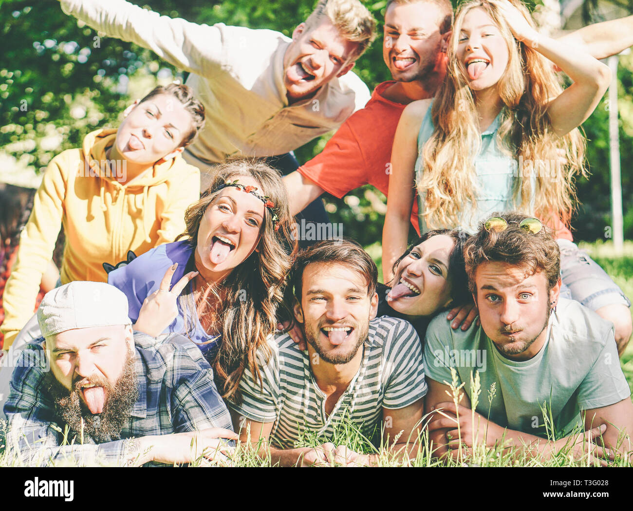 Group of friends having fun together lying on grass while making a self ...