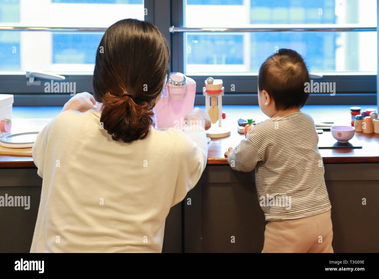 Asian mother and her baby playing with toy kitchen in baby cafe Stock ...