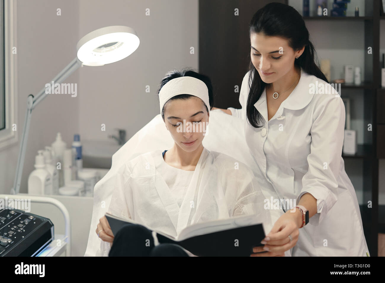 Pretty woman cosmetologist showing to her patient innovations in ...