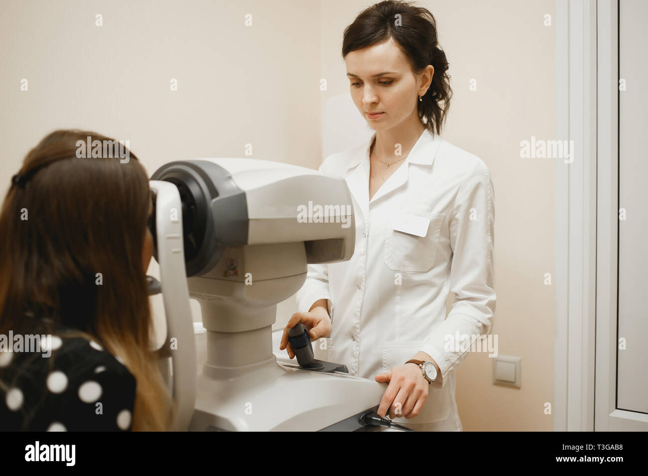 Attractive female doctor ophthalmologist is checking the eye vision of ...