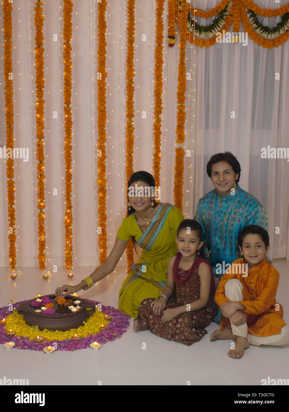 PORTRAIT OF AN INDIAN FAMILY OF FOUR CELEBRATING THE FESTIVAL OF DIWALI ...