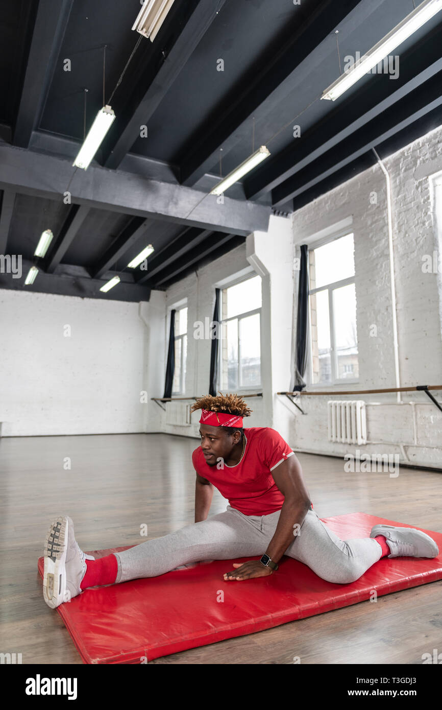 Resolute short-haired fit man stretching his legs for twine Stock Photo ...