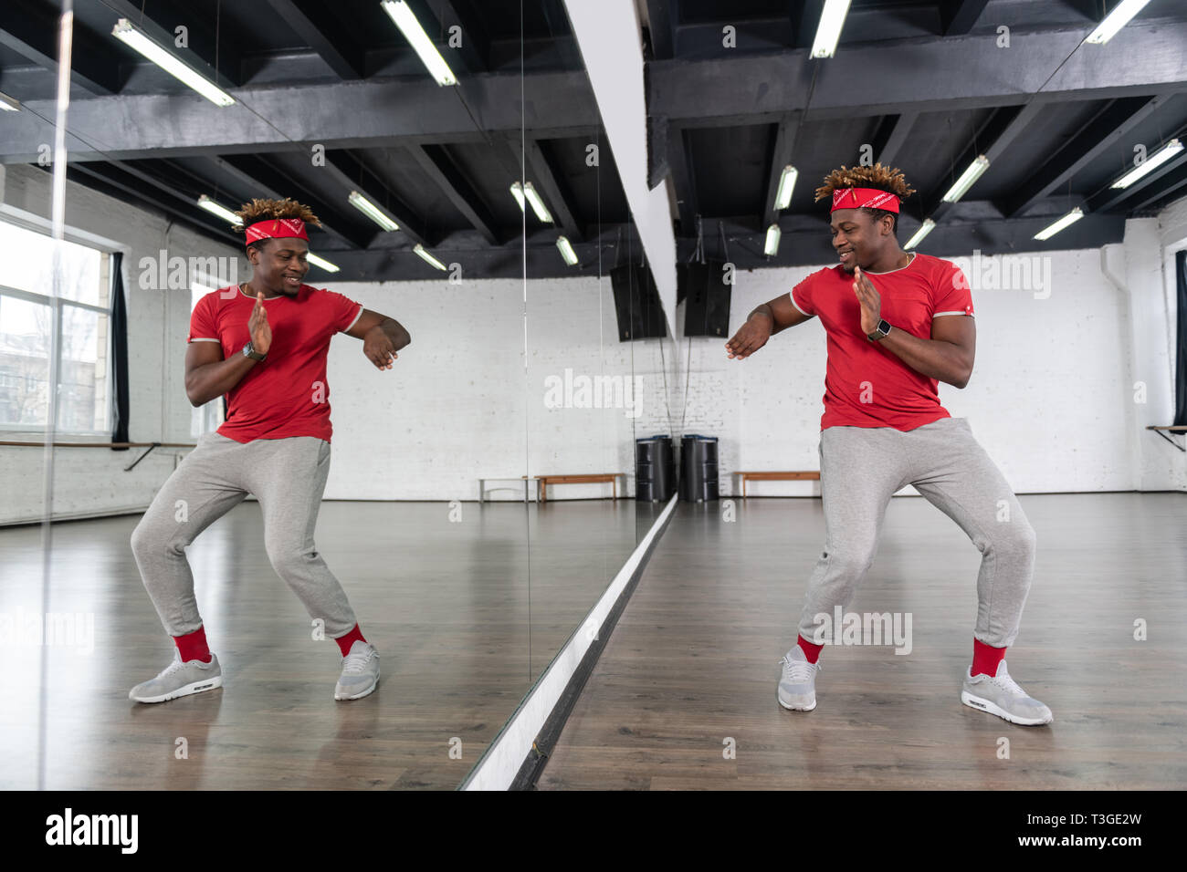 Cheerful short-haired man with dreadlocks squatting during dance Stock ...