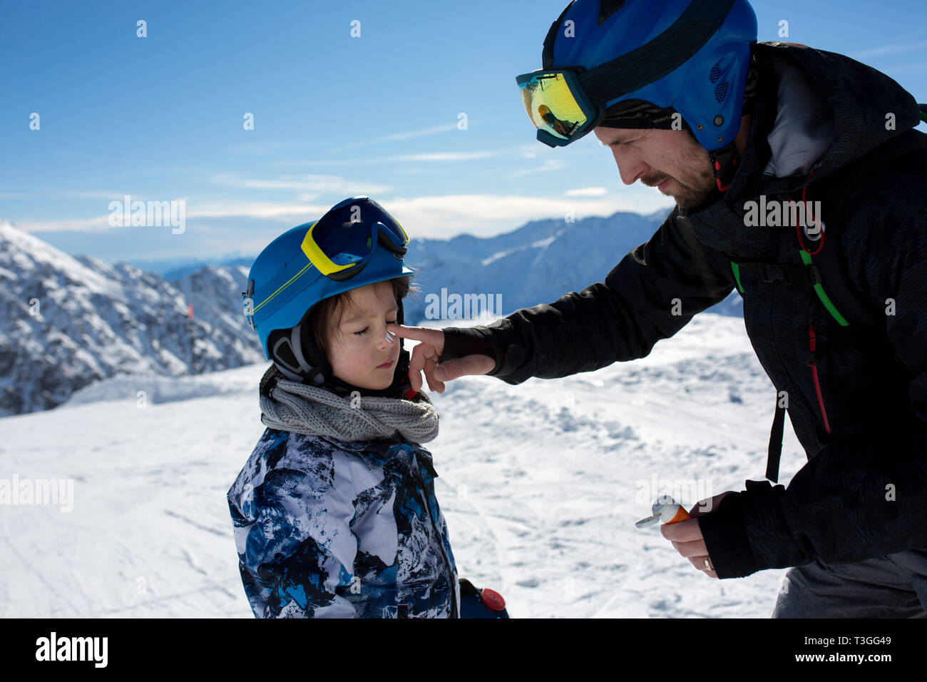 Parent, father, putting sun cream on child's face on top of mountain ...