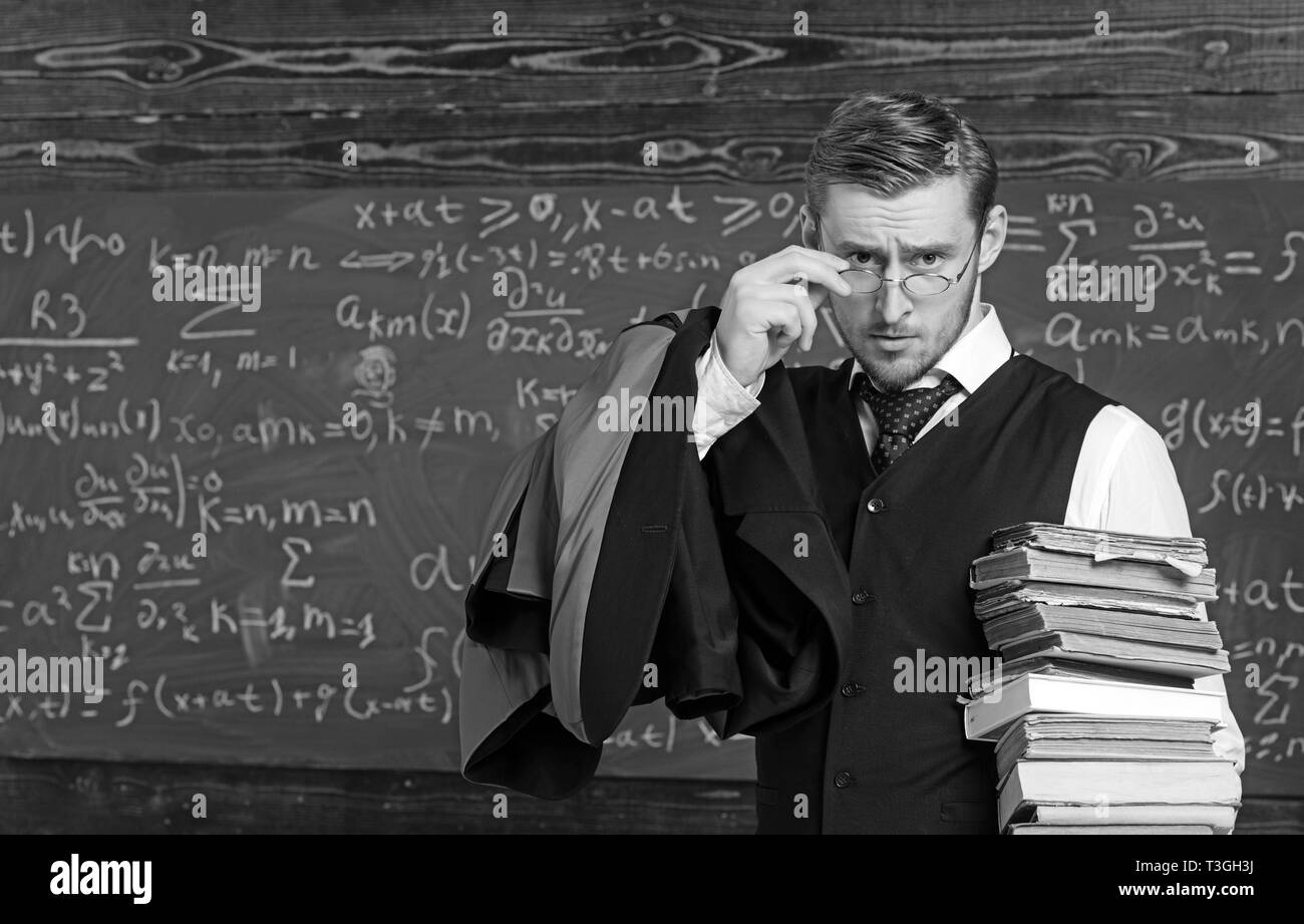 Young professor holding pile of books looking over his glasses ...