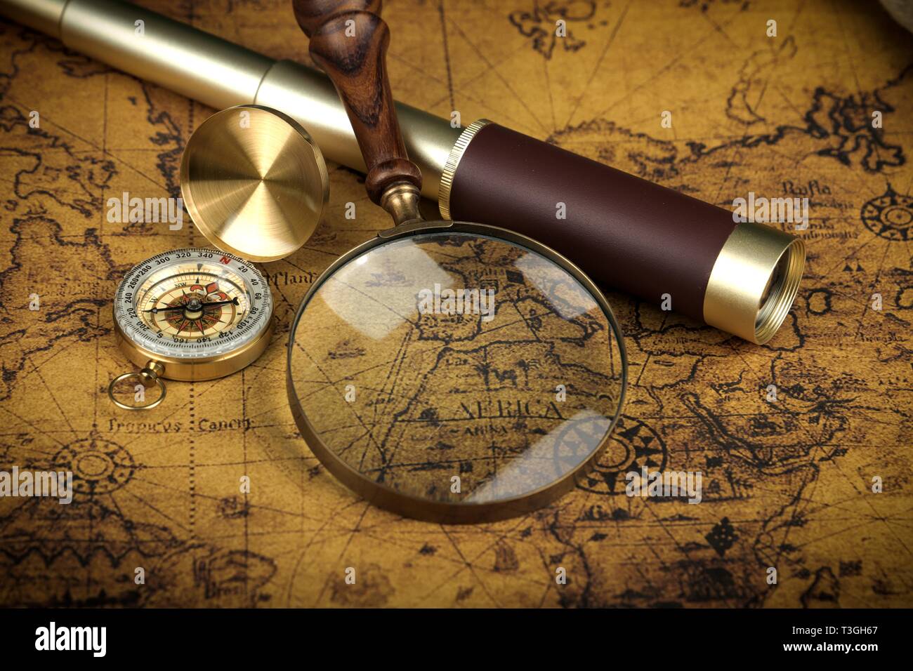 Vintage compass, spyglass and magnifying glass lies on an ancient world ...