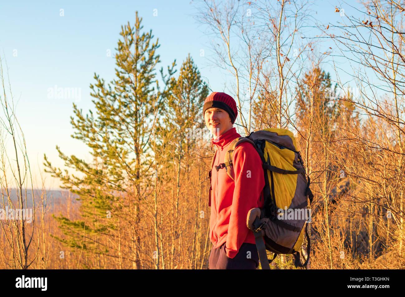 man backpacker stands in forest at sunset in fall in yellow trees Stock ...