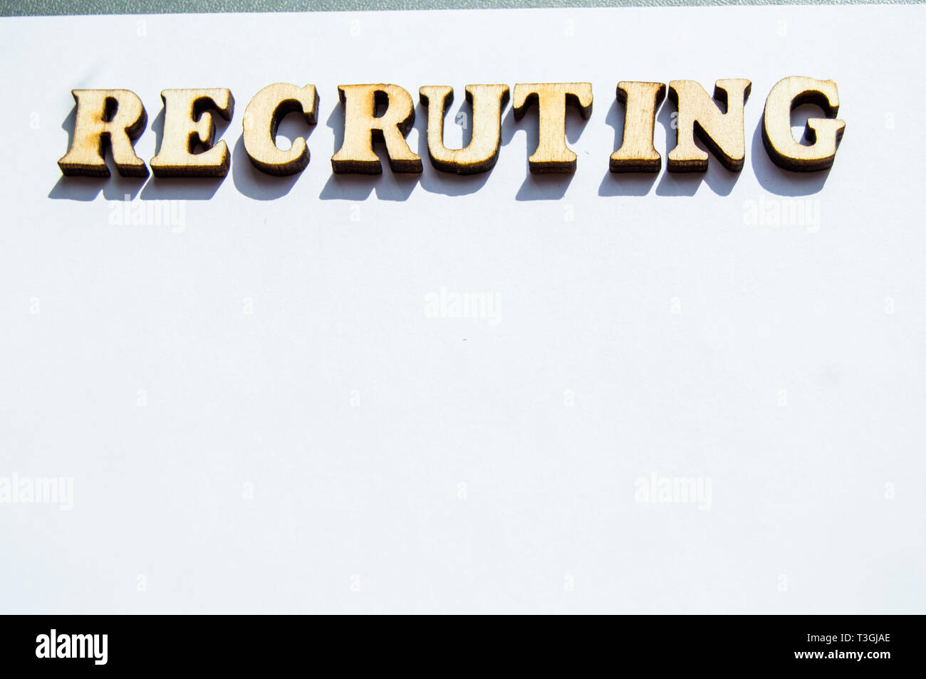 The word recruiting is written in wooden letters on a white background ...