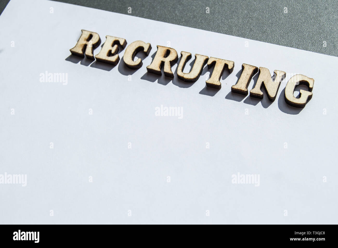 The word recruiting is written in wooden letters on a white background ...