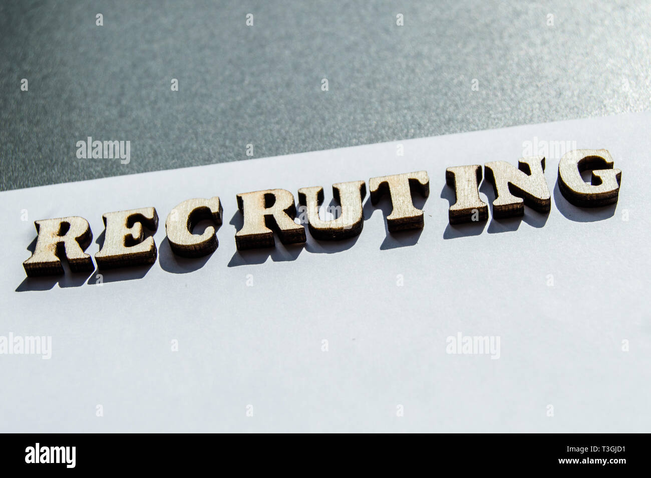 The word recruiting is written in wooden letters on a white background ...