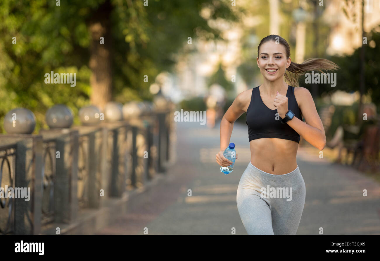 Happy sporty millennial woman running on quay Stock Photo - Alamy