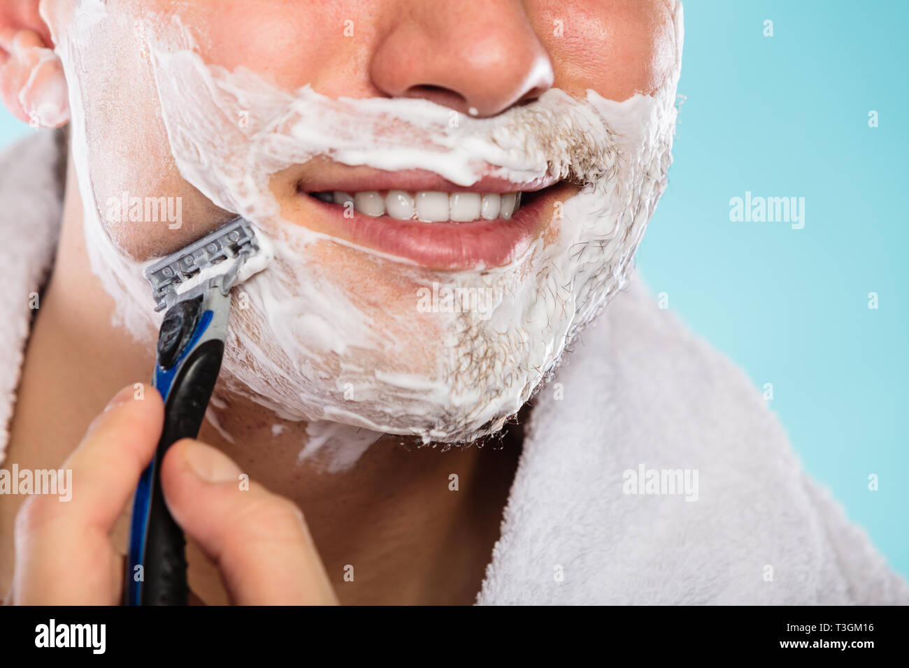 Man shaving using razor with cream foam. Guy removing face beard hair. Skin care and hygiene ...