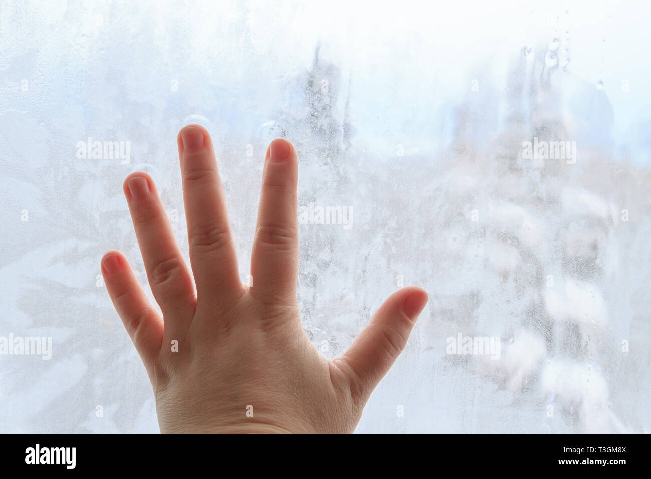 Hand on frozen winter cold window with patterns Stock Photo - Alamy