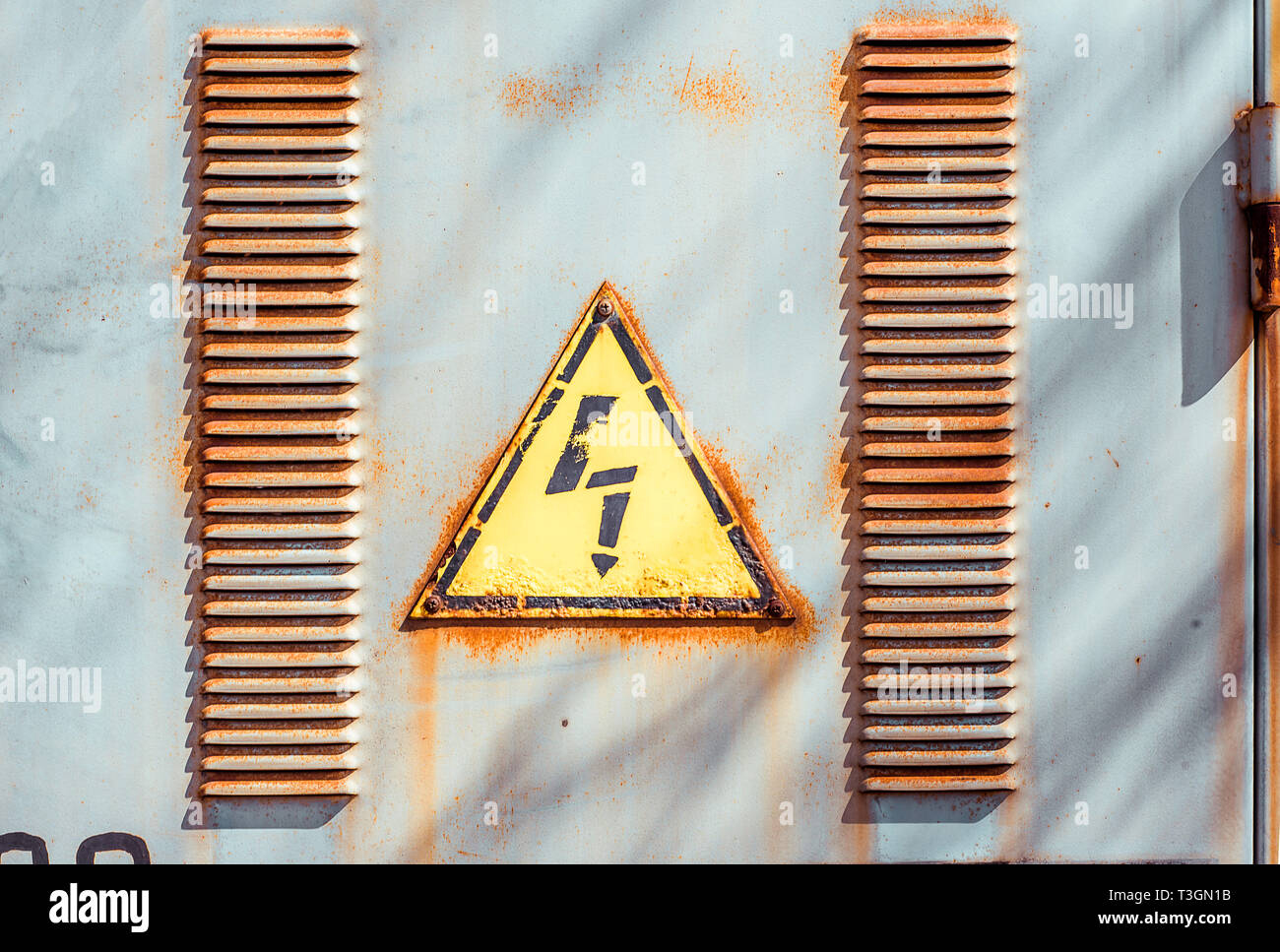 Yellow sign danger electricity between two rows of perforated air vents ...